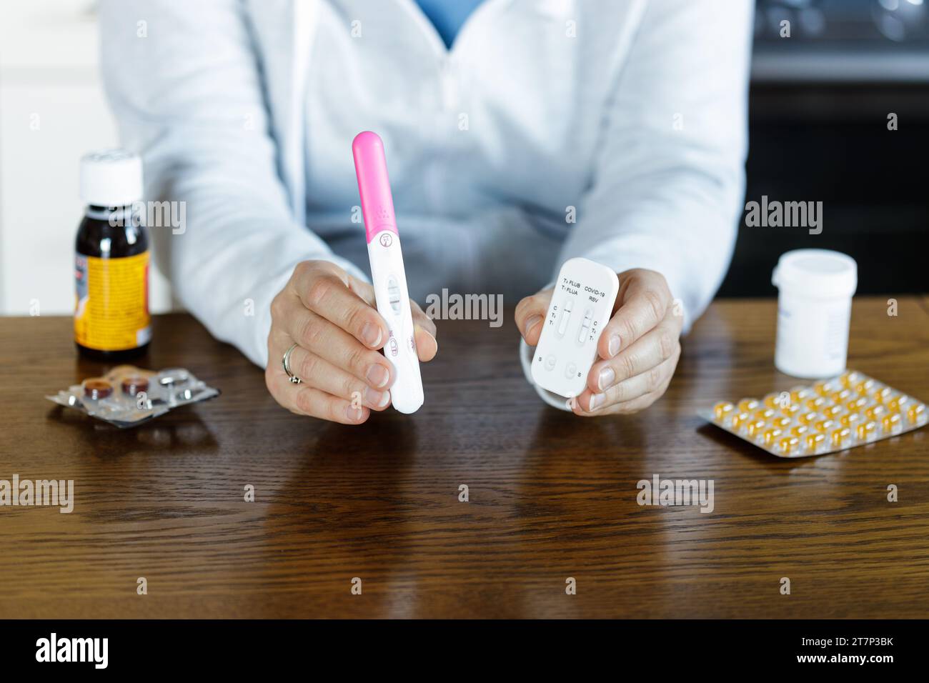 Woman holding positive pregnancy test and positive COVID test. Pregnant ...