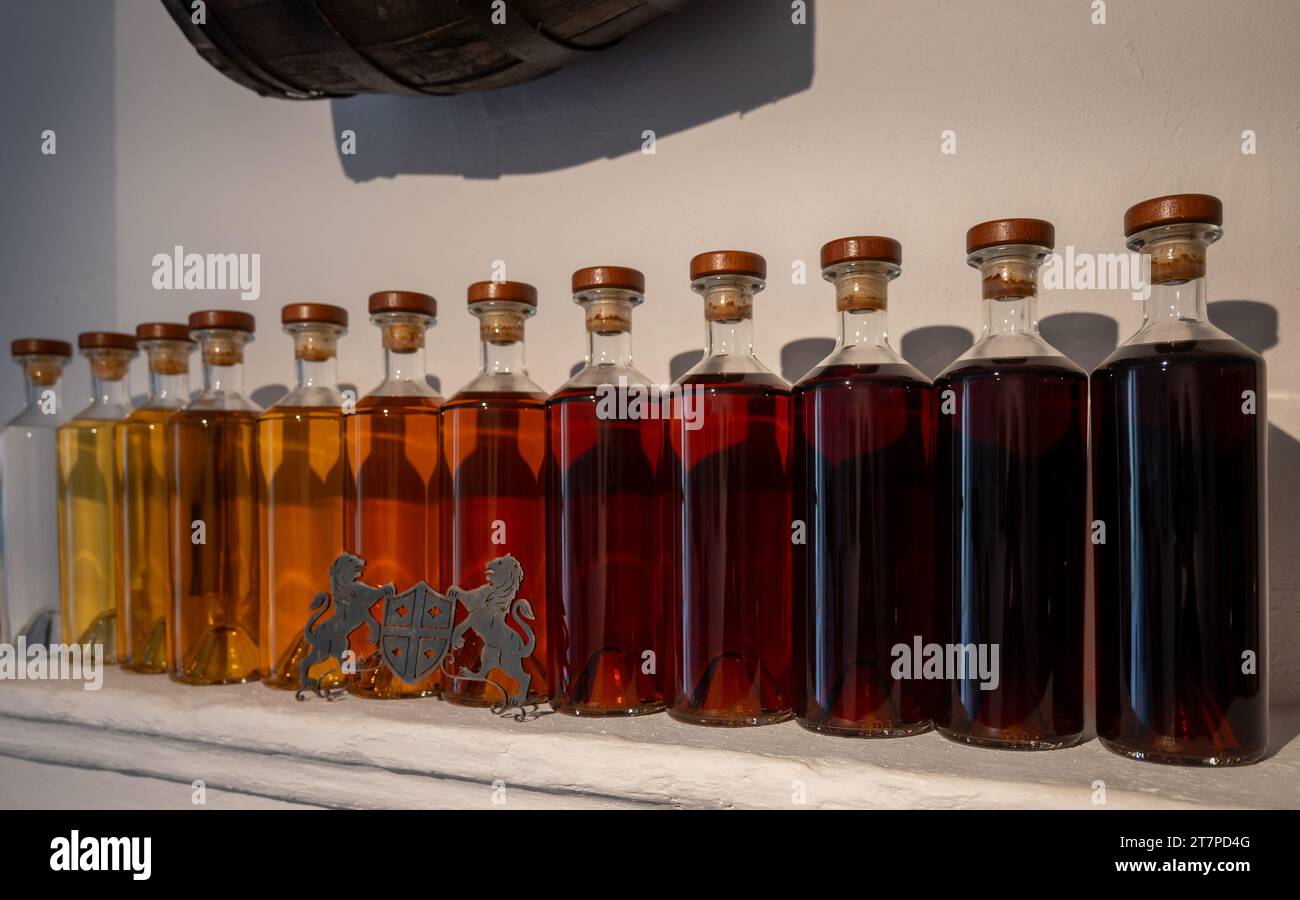 Different colours and ages of cognac spirits in bottles in distillery ...
