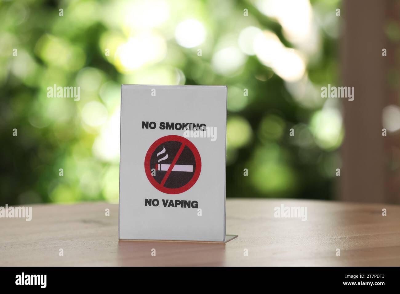 No Smoking No Vaping sign on wooden table against blurred background ...