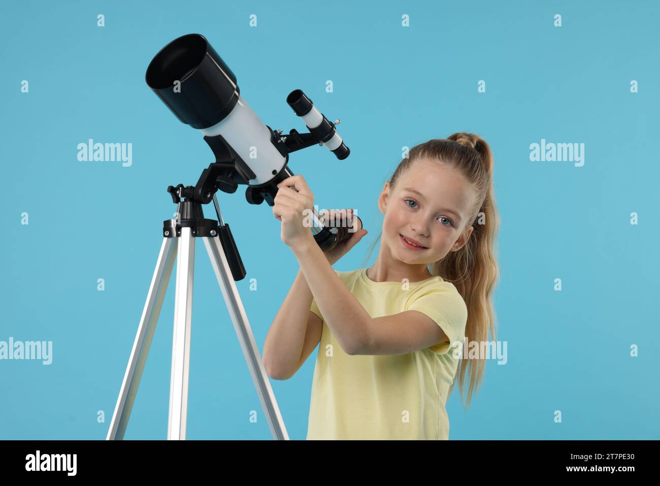 Happy little girl with telescope on light blue background Stock Photo ...