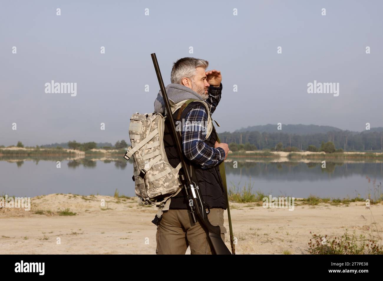 Man with hunting rifle and backpack near lake outdoors Stock Photo - Alamy