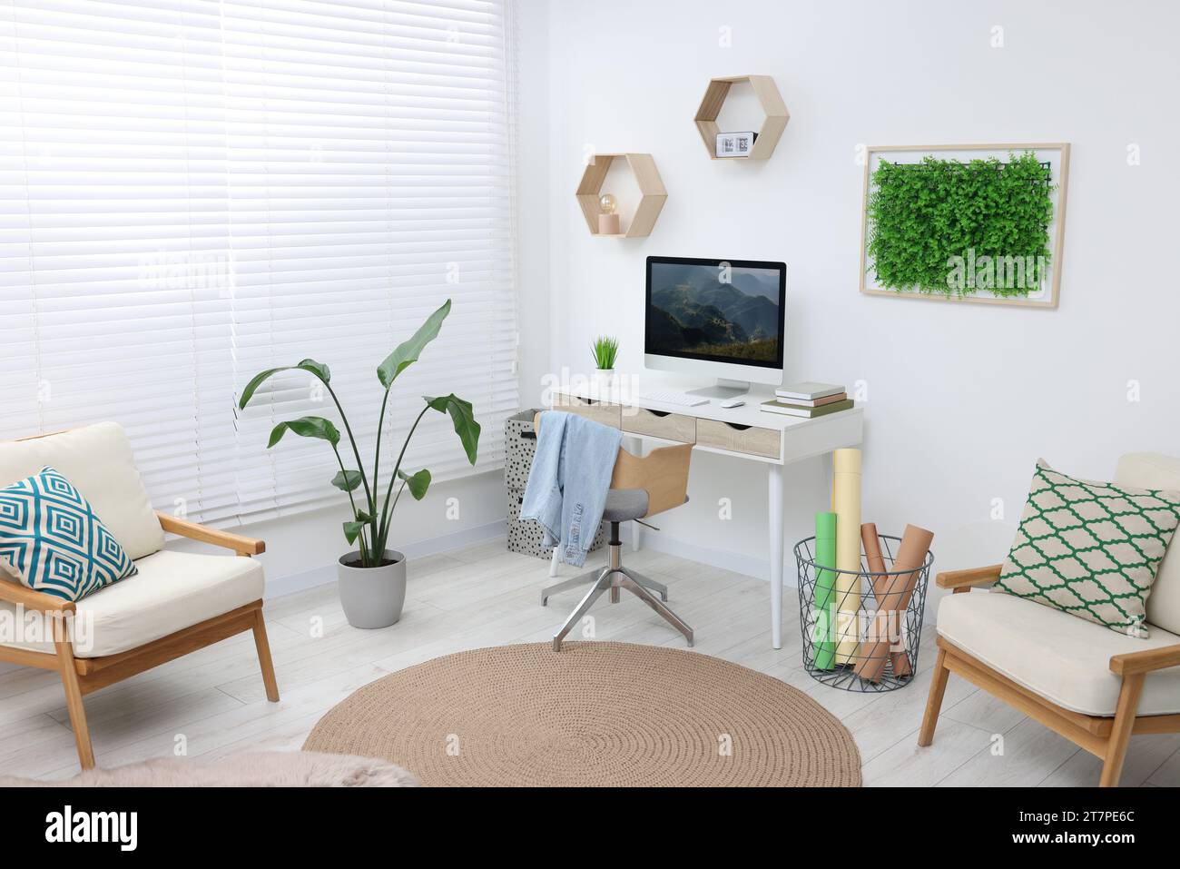 Green artificial plant wall panel and desk with computer in light room ...