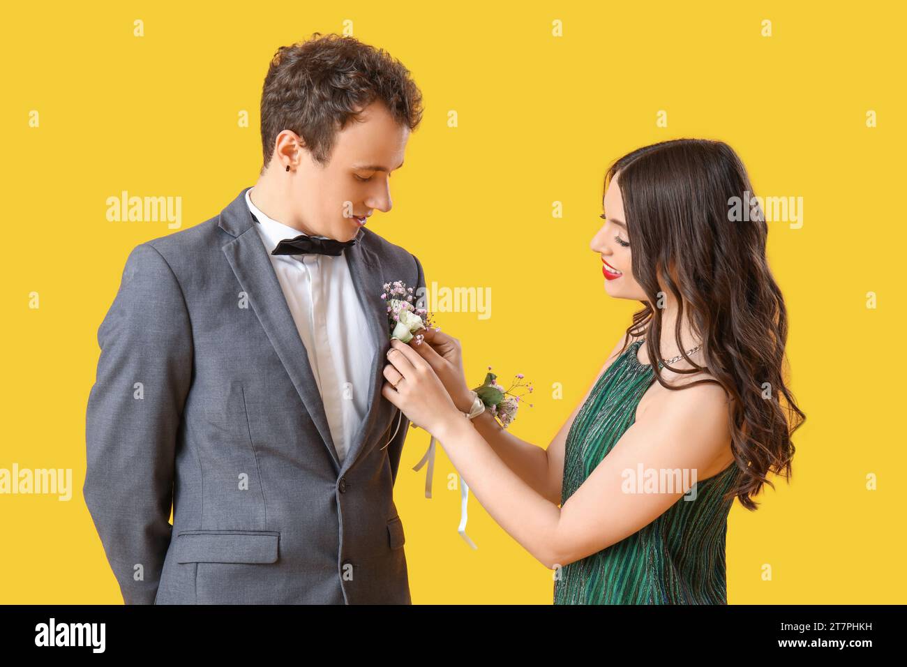 Beautiful prom couple pinning boutonniere on yellow background Stock ...