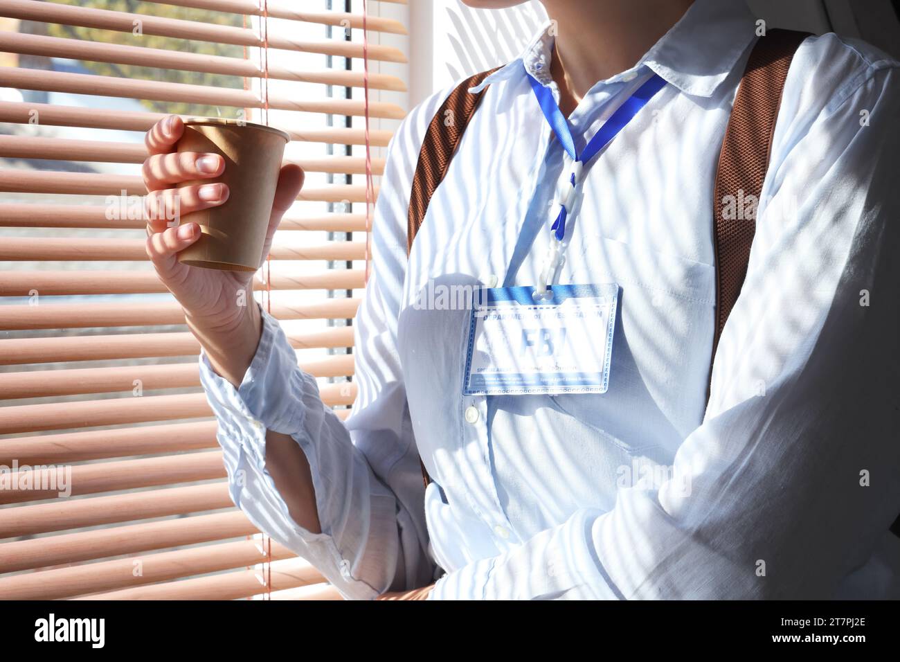 Female FBI agent with cup of coffee near window in office, closeup ...
