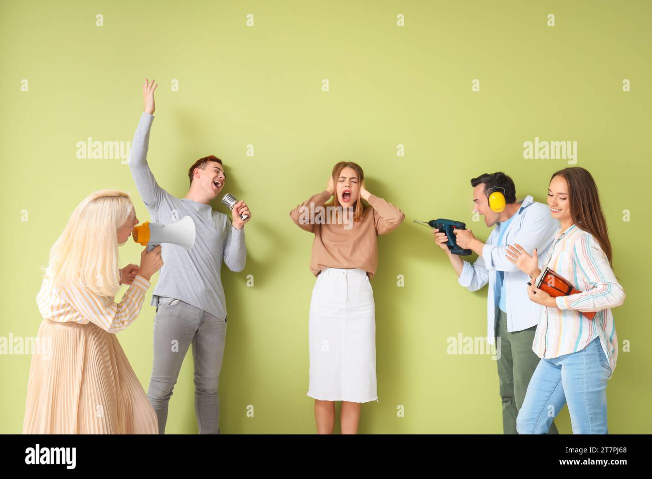 Young woman suffering from noisy neighbours on green background Stock ...
