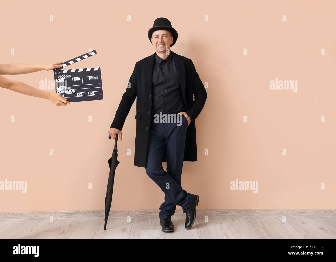 Mature actor and hands with clapperboard near beige wall Stock Photo ...