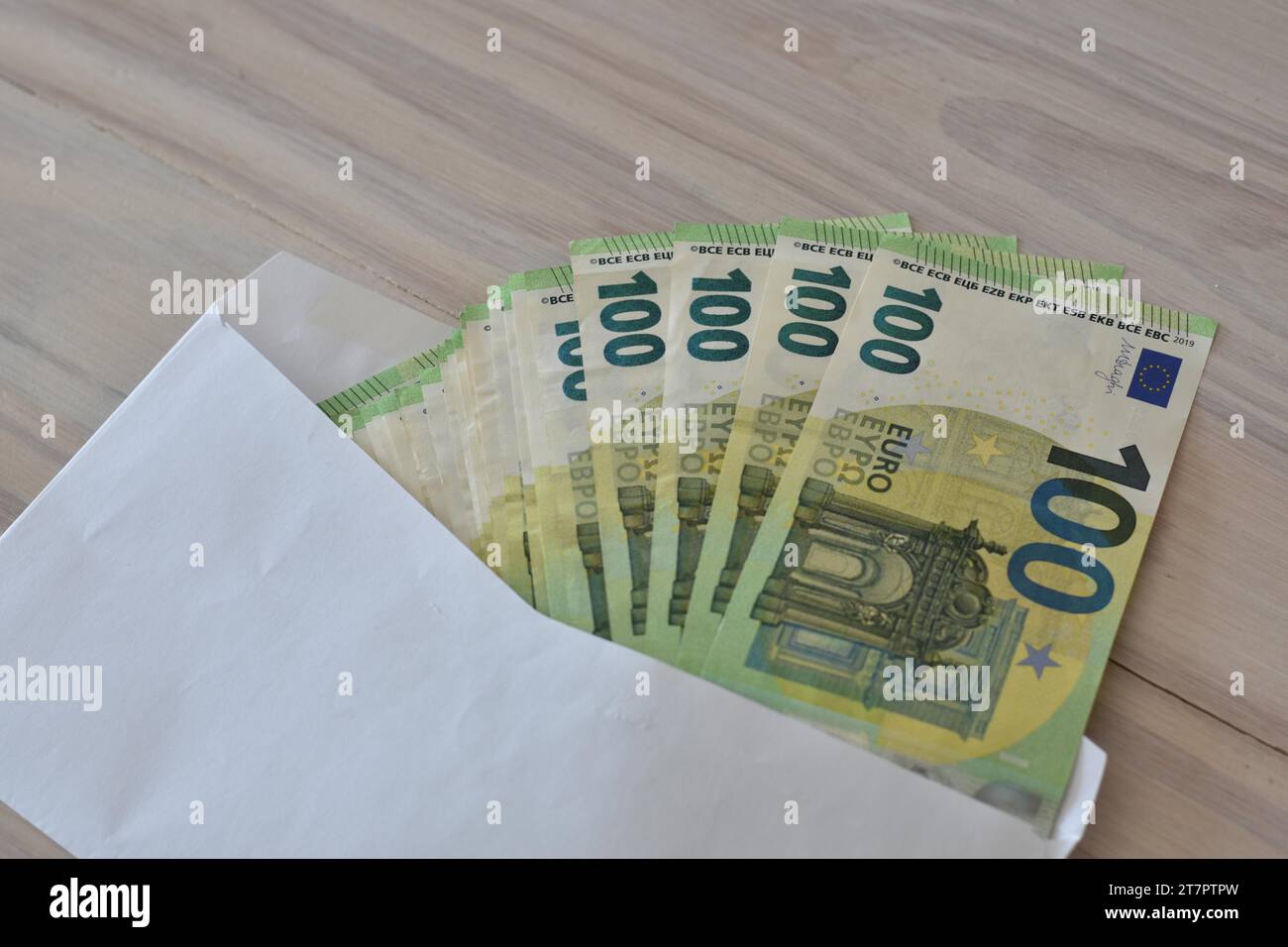 Many one hundred euro notes in an envelope on a table, symbolising cash ...