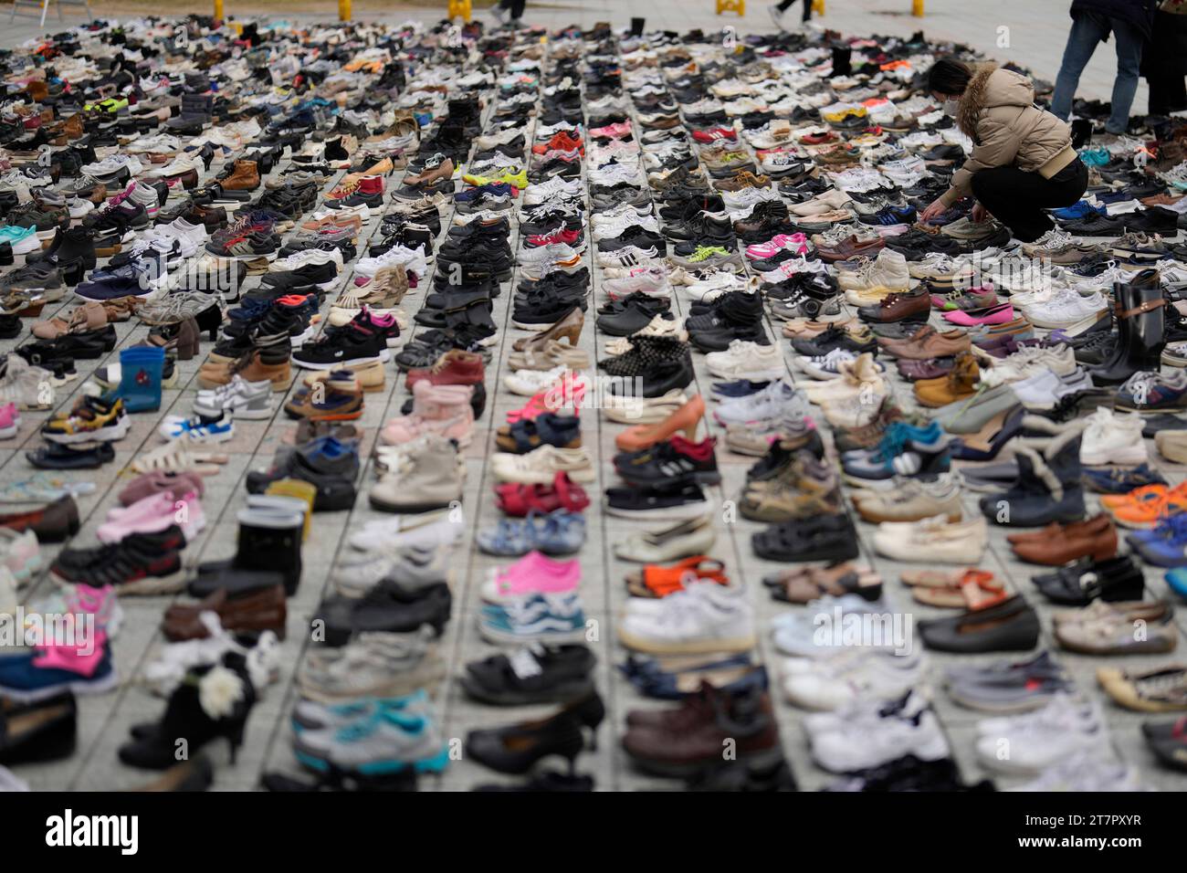 A member of civic groups adjusts pairs of shoes symbolizing all the ...