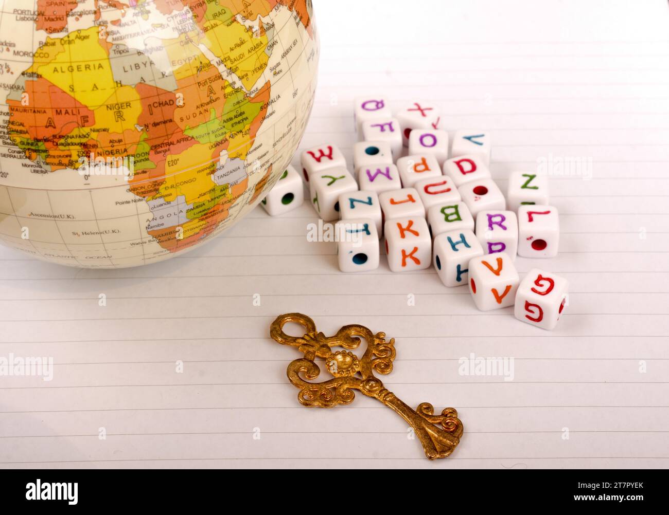 Globe, key and cube letters of alphabet side by side on a white paper ...