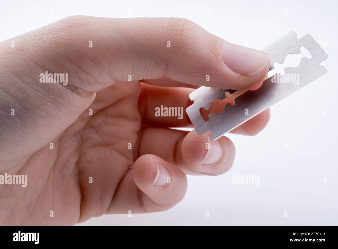 Hand holding a razor blade on a white background Stock Photo - Alamy