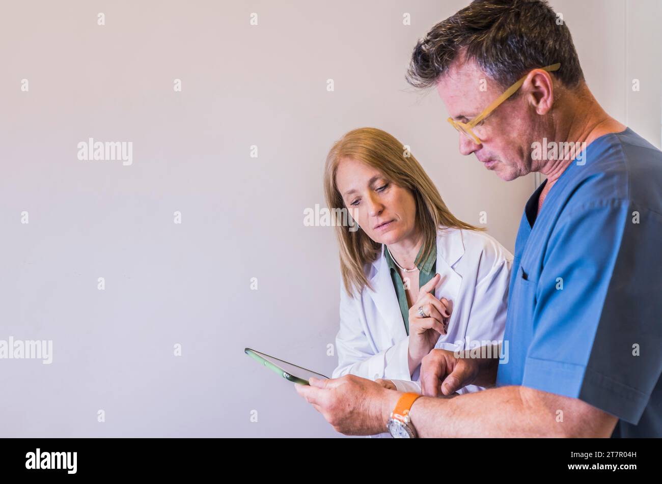 Concentrated doctors using pad device while talking about a patient ...