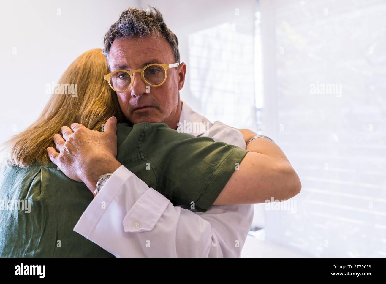 Portrait of serious doctor embracing a female patient after giving her ...