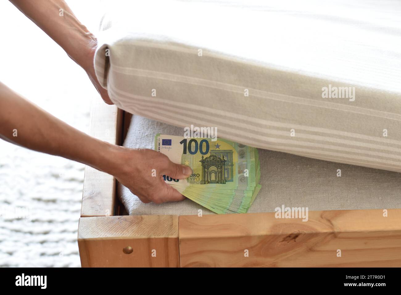 A hand deposits many hundred euro banknotes under a mattress ...