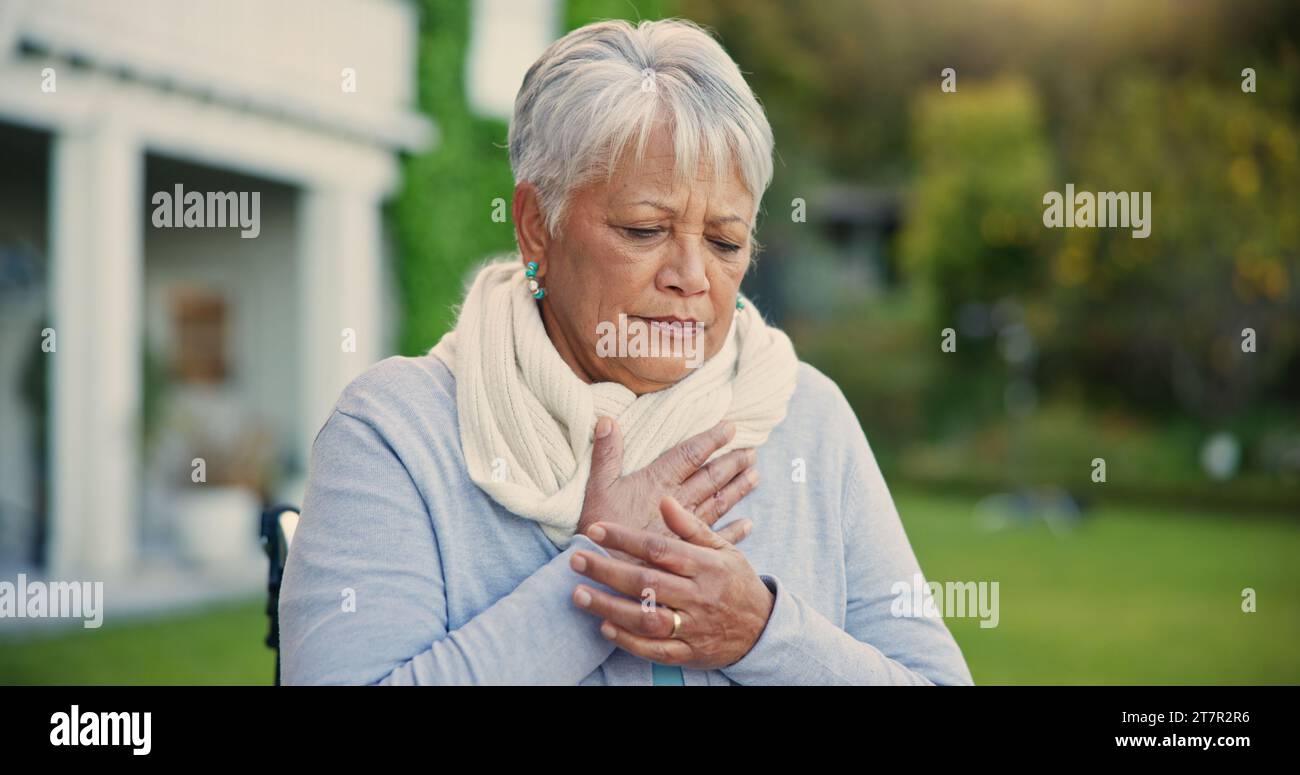 Heart attack, pain and senior woman in a garden with hands on chest ...
