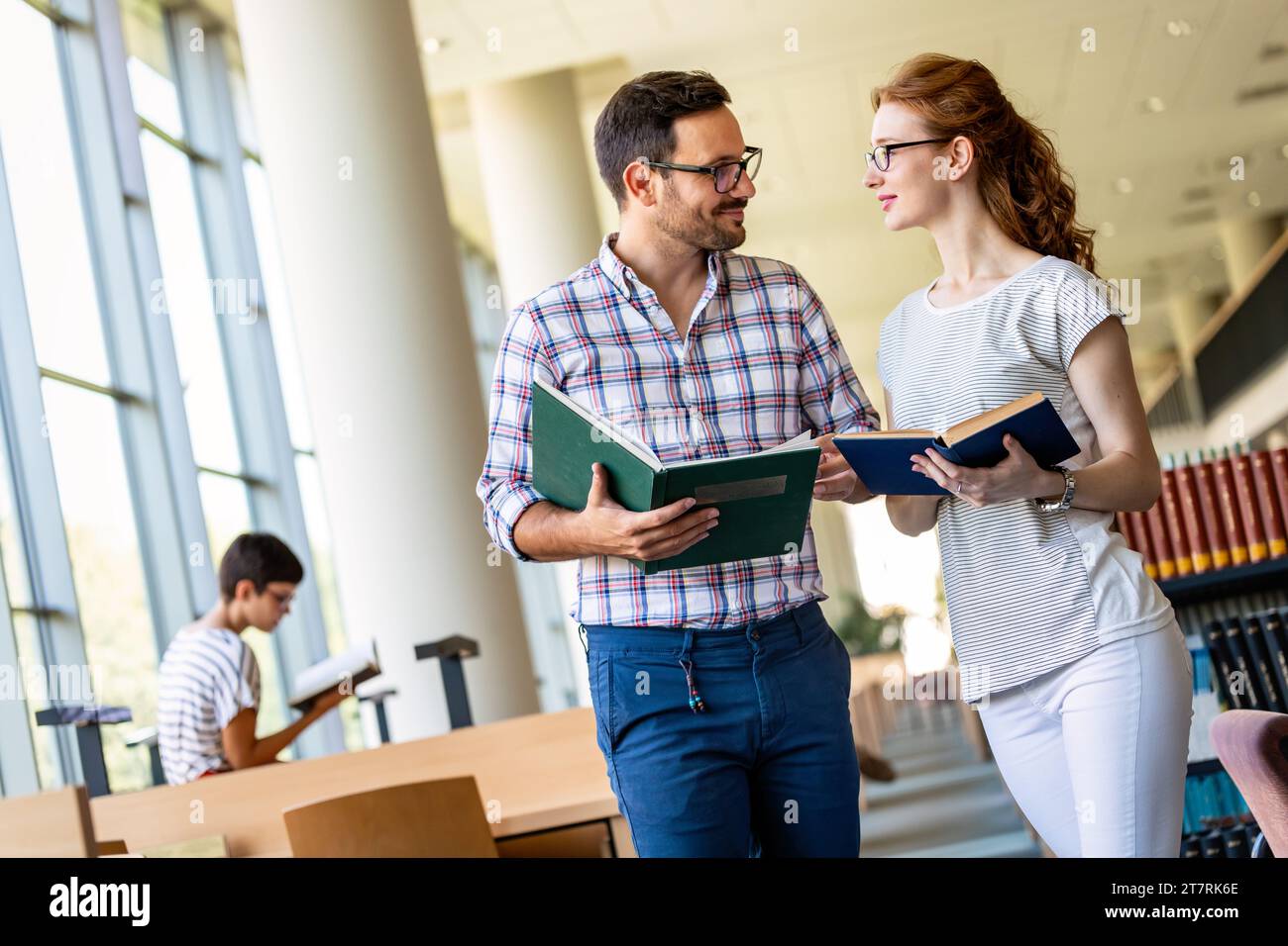 Happy university students studying with books in library. Group of ...