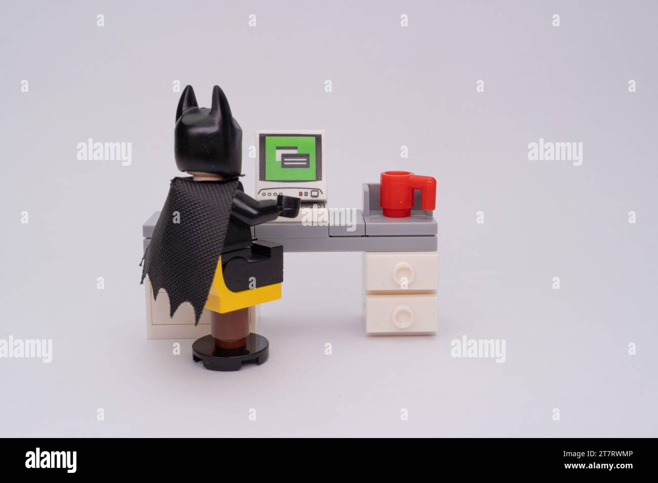 A Lego figurine of Batman sitting on a computer desk made of Lego ...