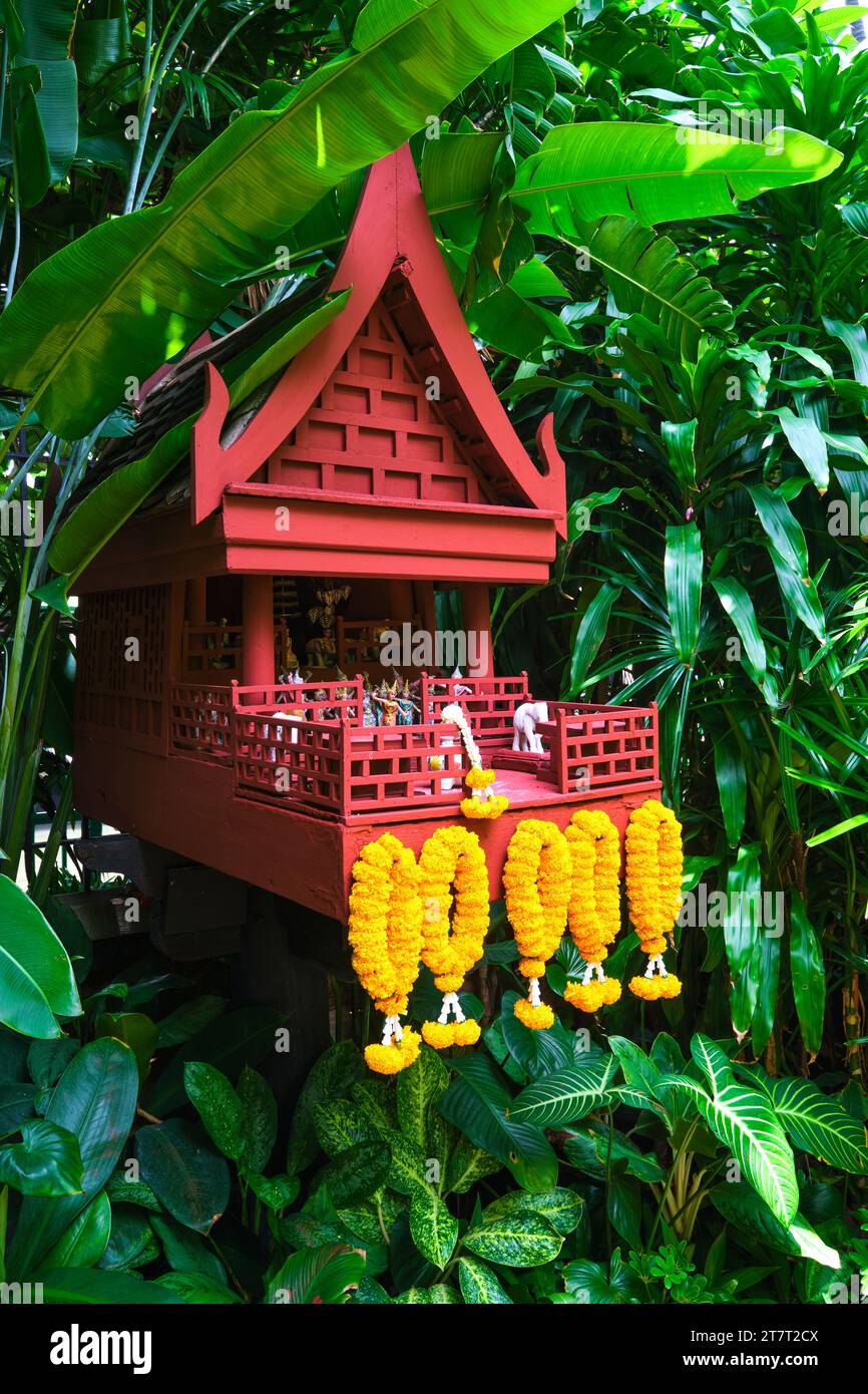 A small, wooden altar with fresh yellow pooja flowers hanging from the ...