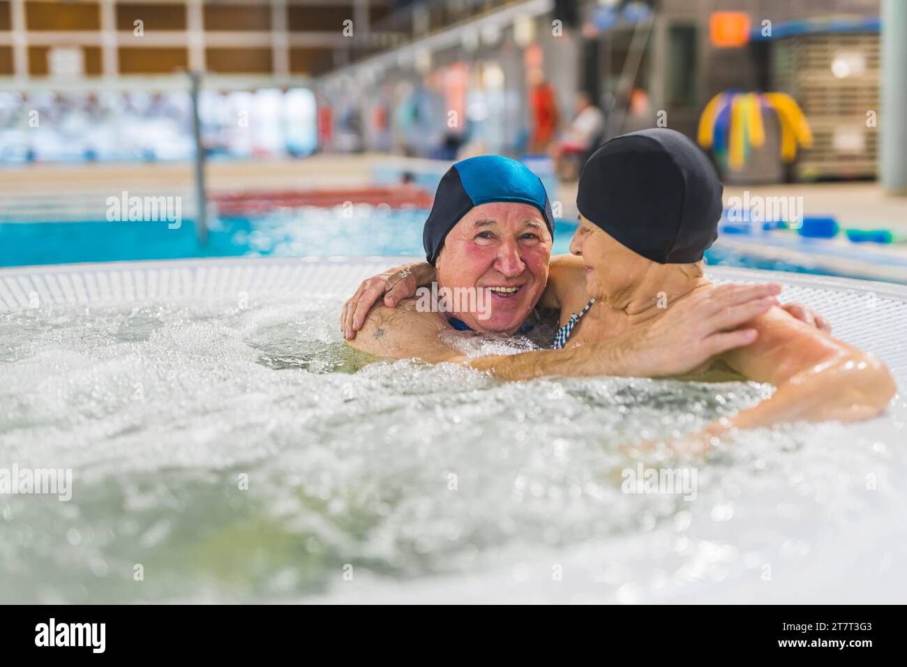 Senior couple hugging together in the swimming pool and relaxing. High ...