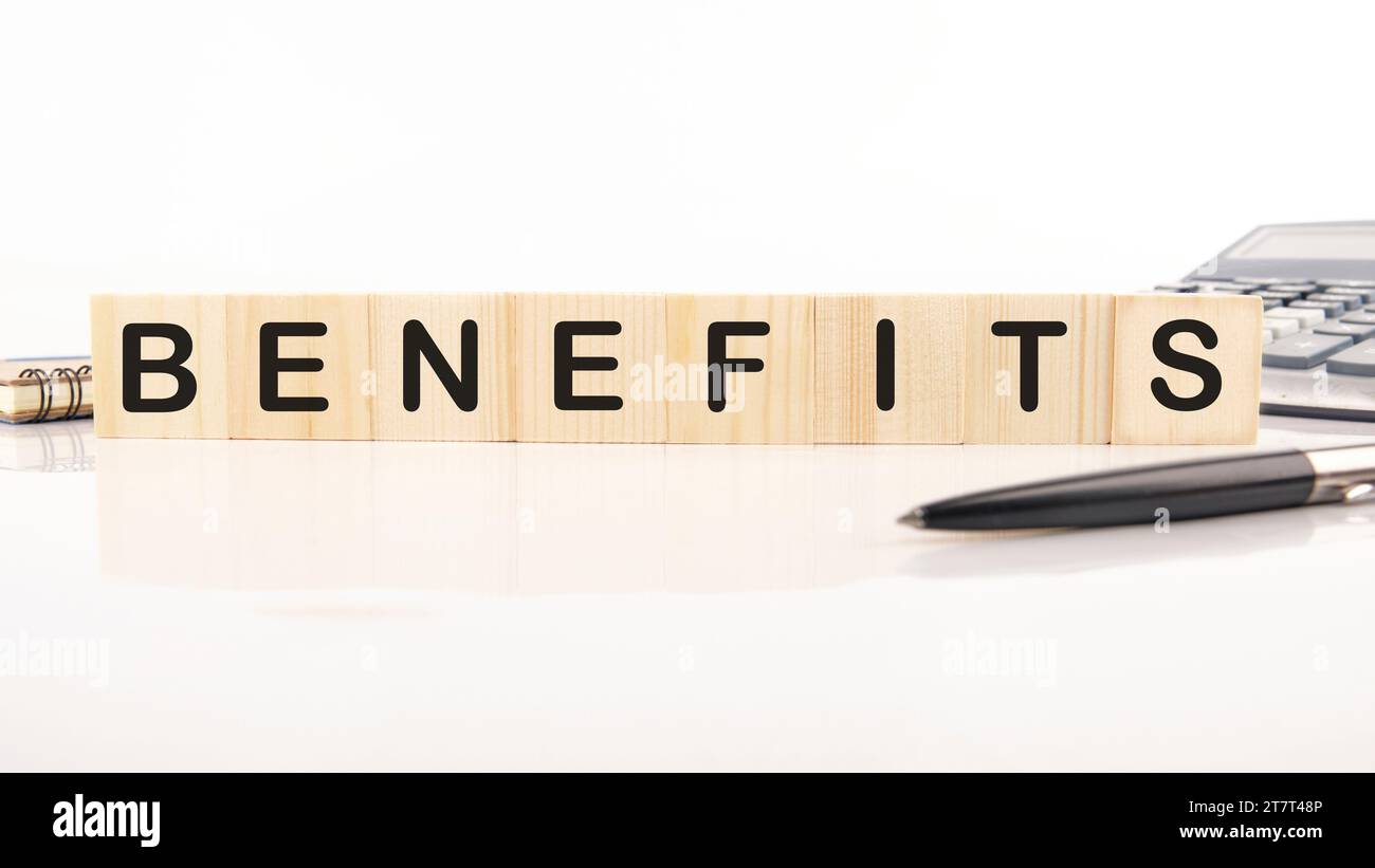 BENEFITS word word assembled from wooden cubes next to a calculator ...