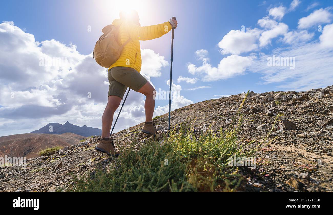 Hiker with backpack and trekking pole ascending a mountain trail under ...