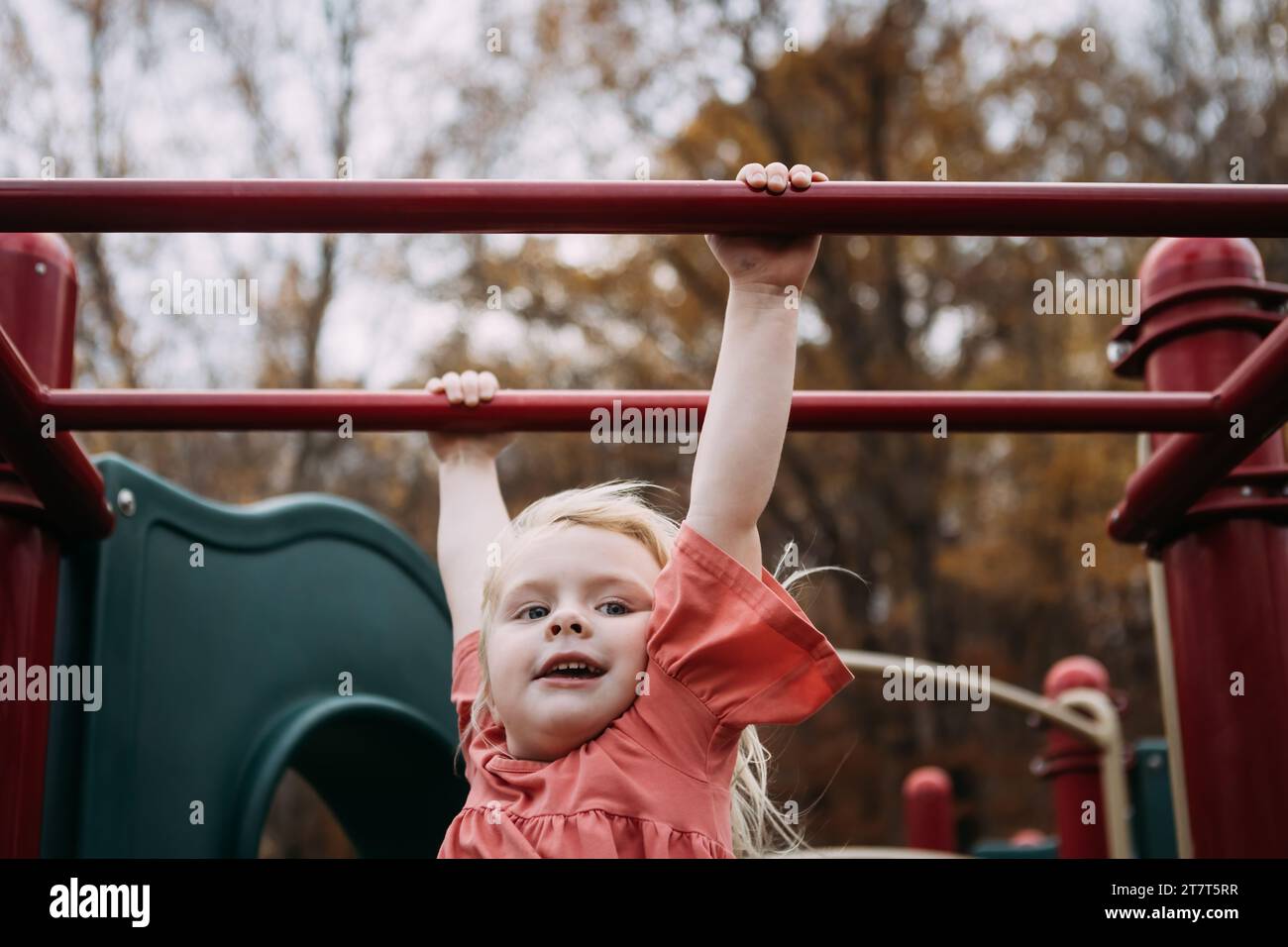 Young girl at playground hanging on monkey bars Stock Photo - Alamy