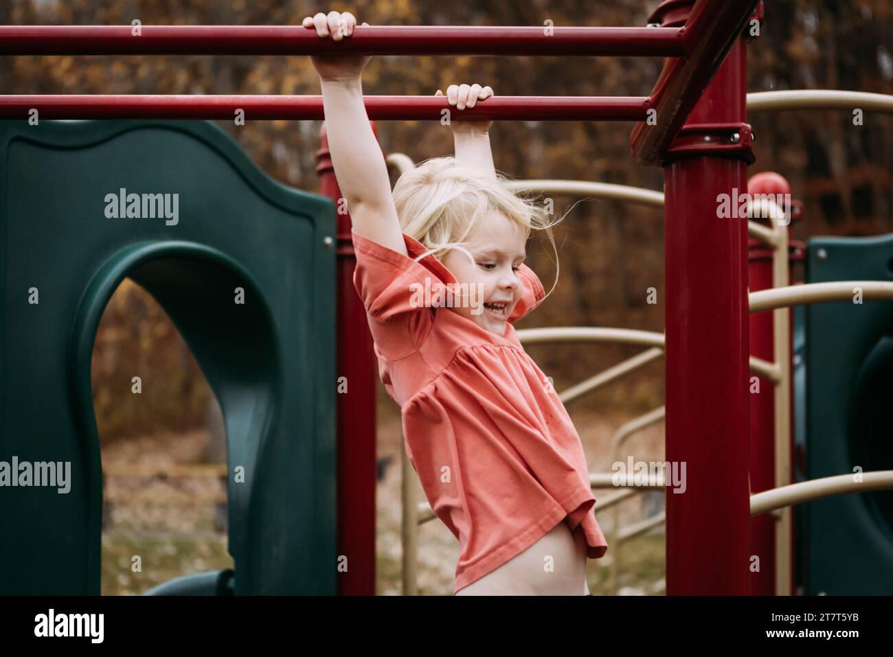 Young girl playing on monkey bars at playground Stock Photo - Alamy