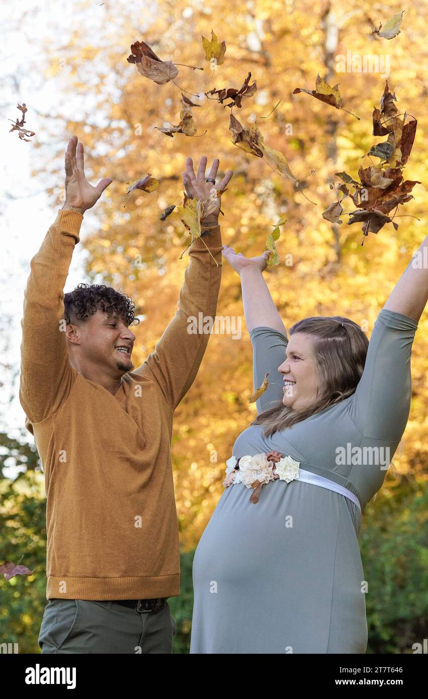 Man & pregnant woman with hands up and leaves falling Stock Photo - Alamy