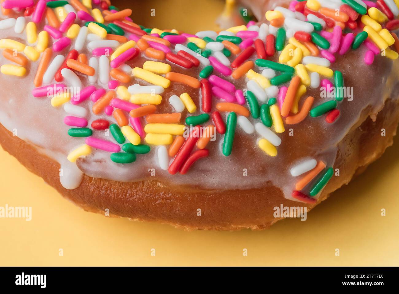 Vanilla Frosted Rainbow Sprinkle Donut on a Yellow Background Stock ...