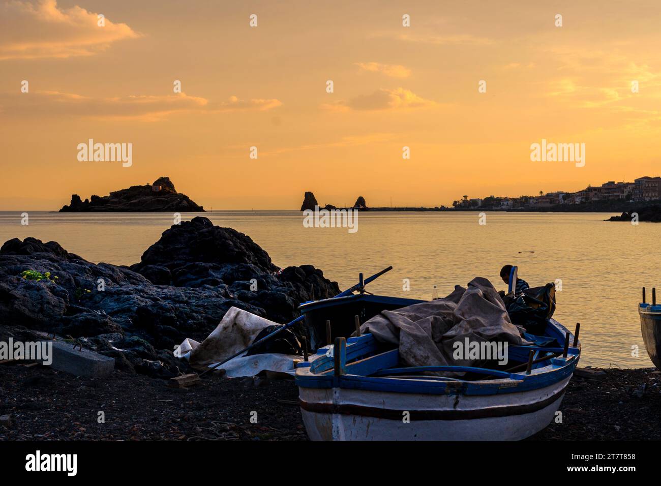 Old fishing boat stranded on pebble beach near Isola Lachea, the famous ...