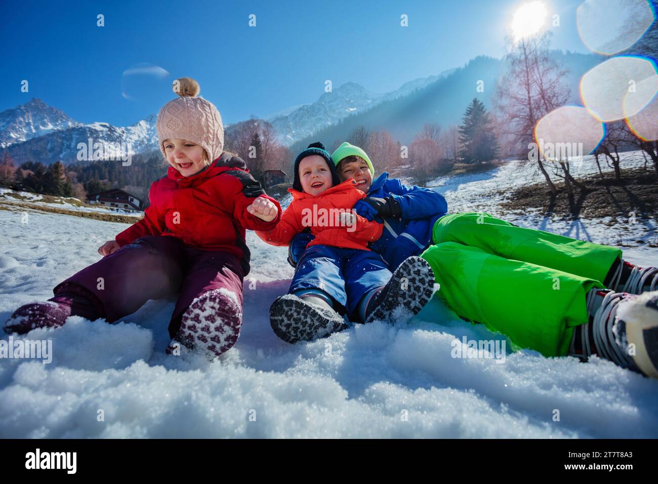 Siblings laughing, roll in snow at sunny snowy mountain camp Stock ...
