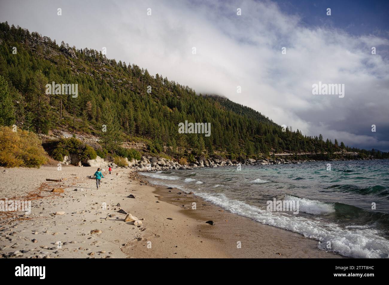 Two boys running in distance along beach of lake Stock Photo - Alamy