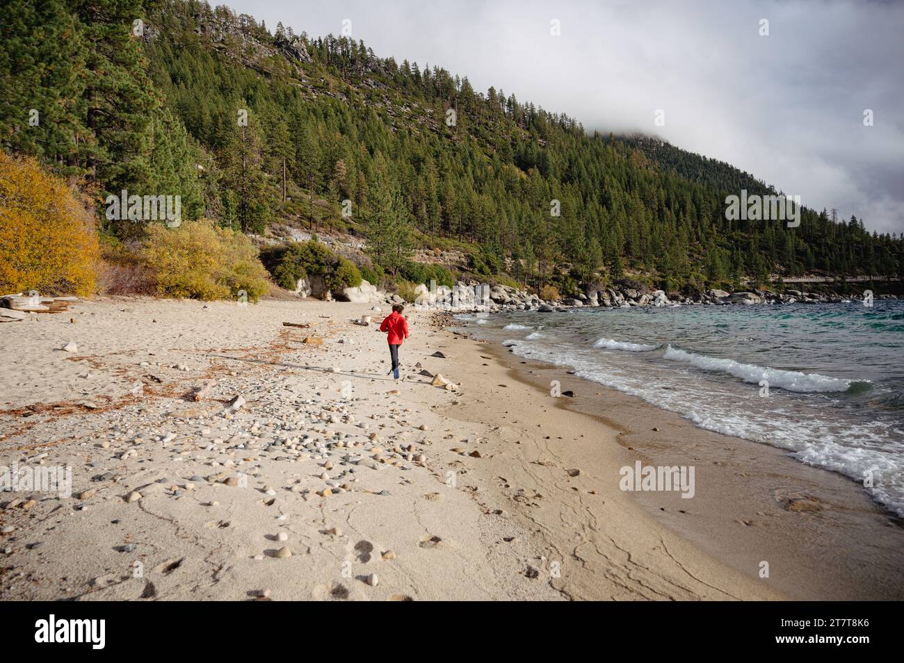 Boy in red jacket running along lakeshore Stock Photo - Alamy