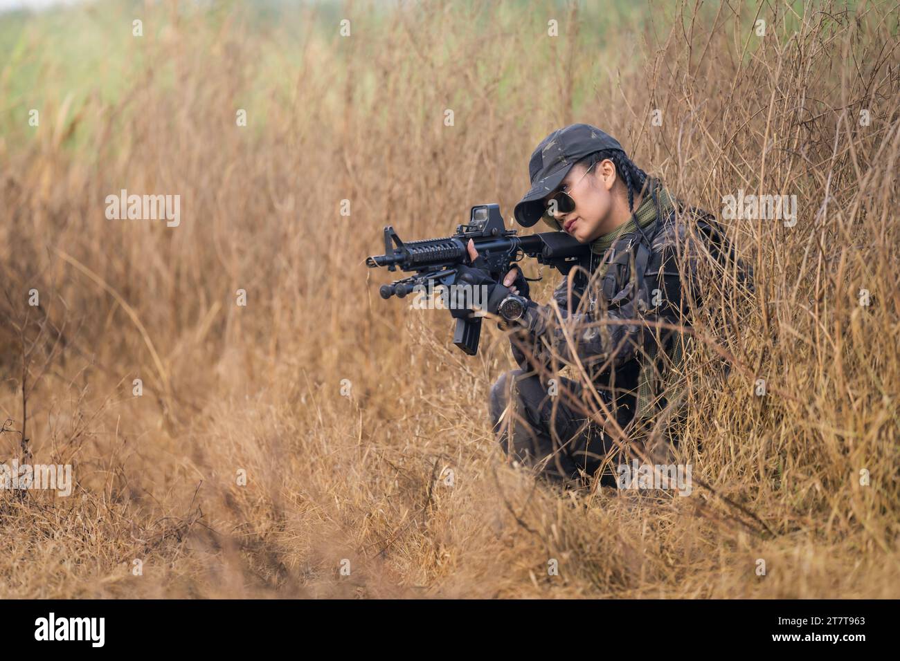 A female wearing tactical gear is kneeling down in a defensive position ...