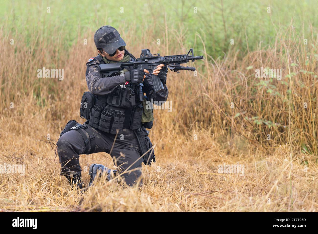 A female wearing tactical gear is kneeling down in a defensive position ...