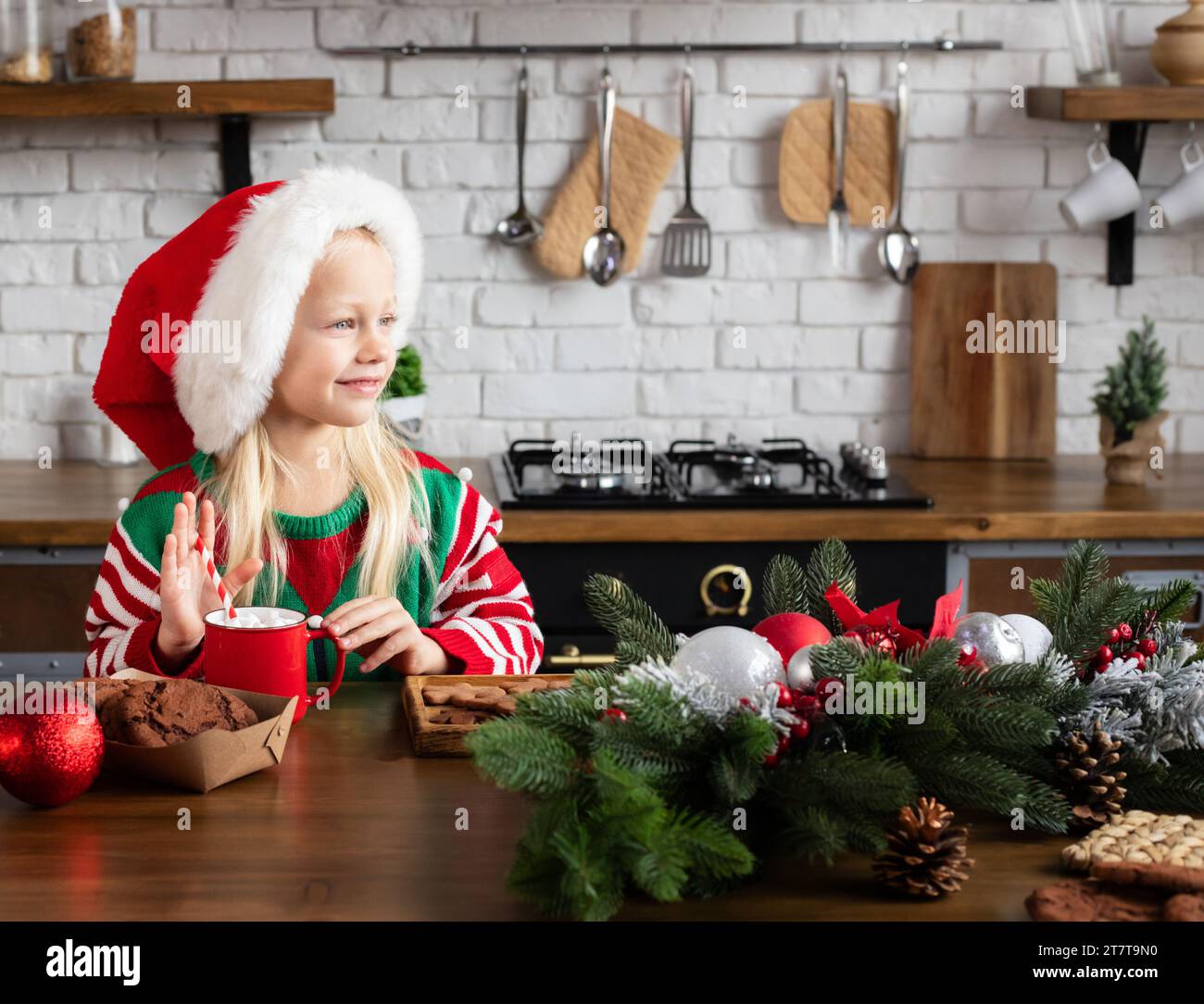 Kid dressed up as elf holding candy cane and smiling. Child sitting at ...