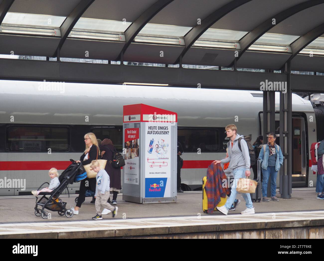 A young family with a stroller and luggage walking on platform in front ...