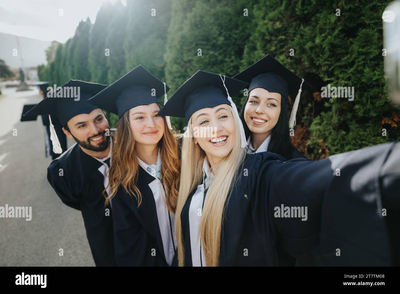 Graduates in gowns and caps celebrate their achievement outdoors ...