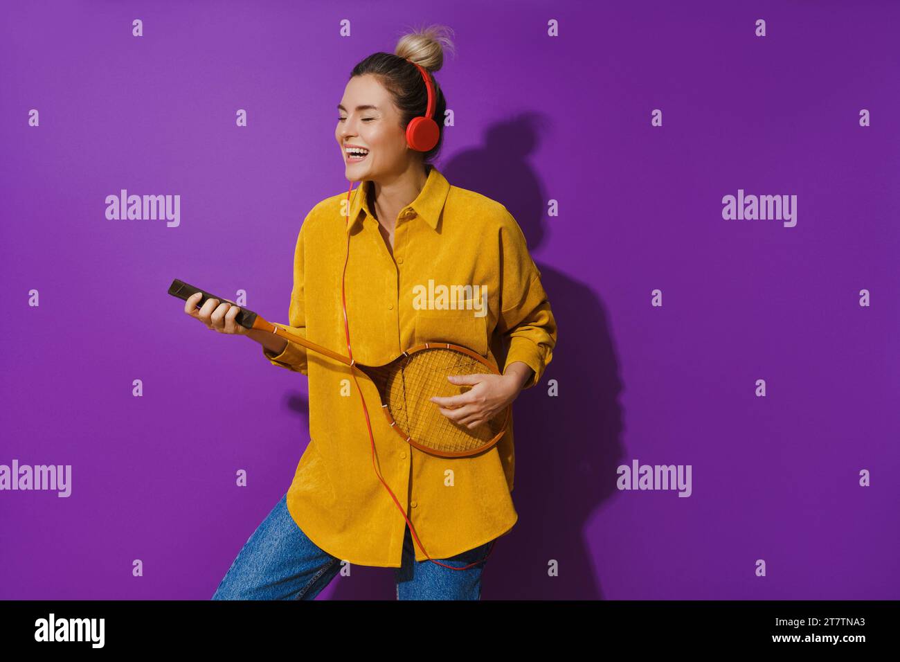 Cheerful girl is jamming out in her yellow shirt while wearing red ...
