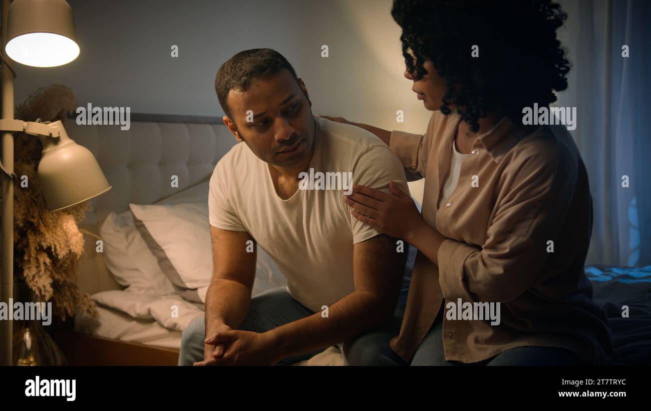African American sad man sit on bed night evening at home suffer ...