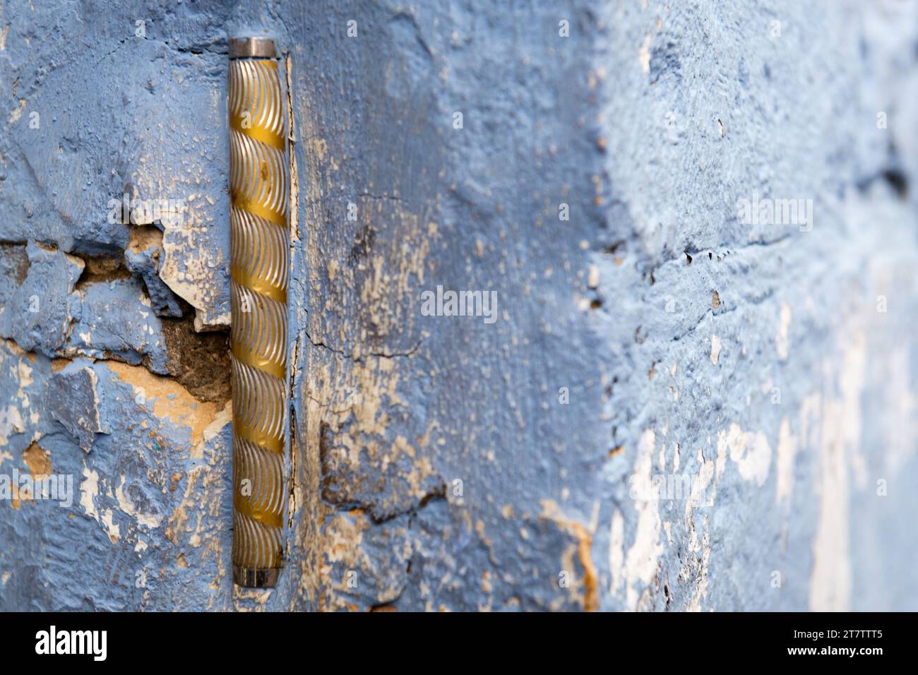 A mezuza scroll is mounted to a stone wall at the entrance to a home in ...