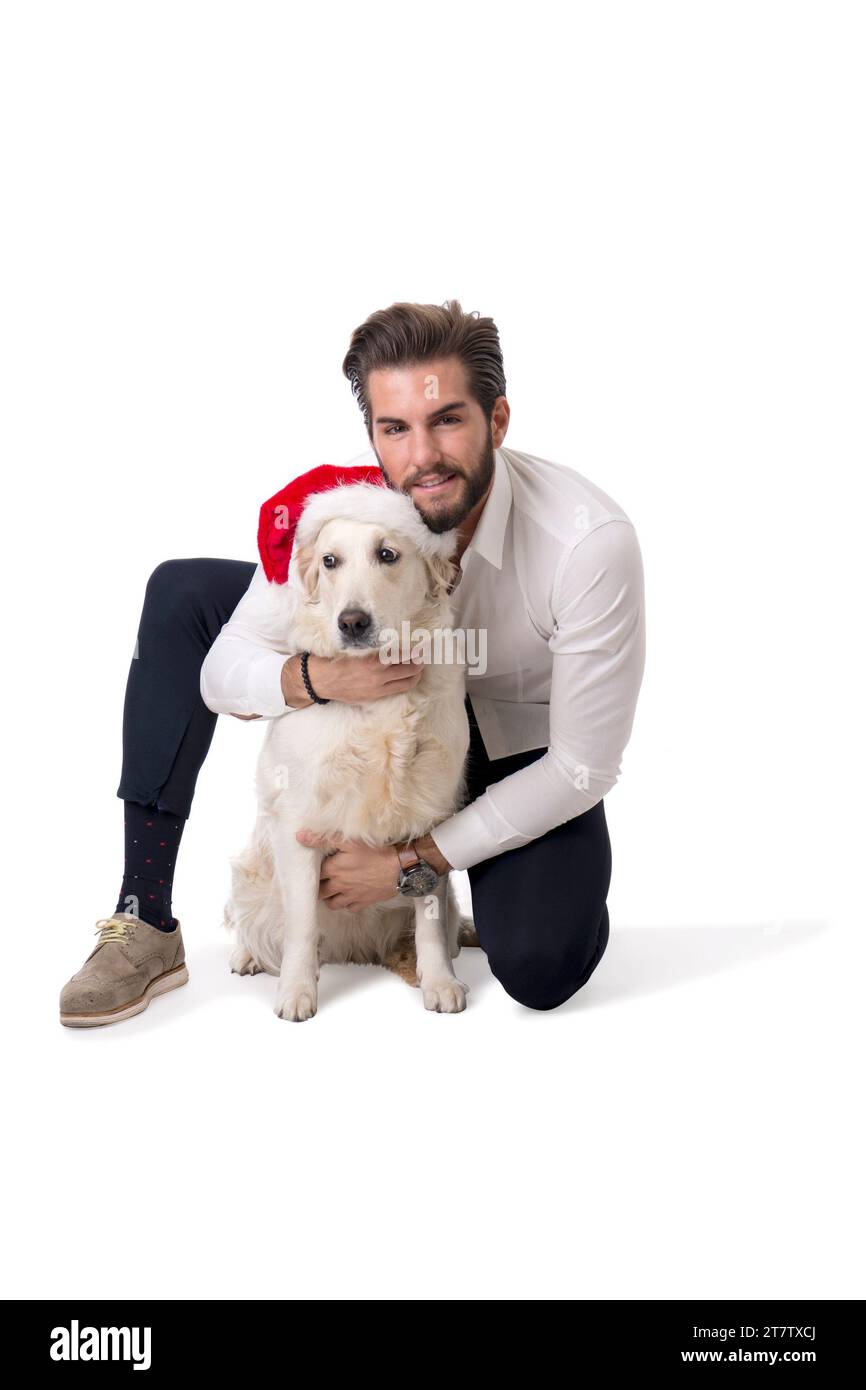 Handsome young man with labrador white dog wearing Santa Claus red hat ...