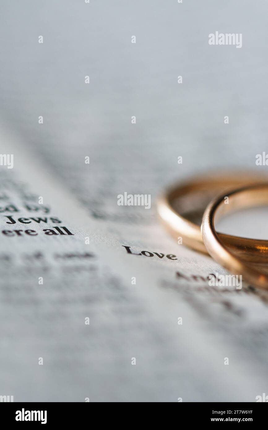 Two golden wedding rings and opened pages of holy bible represents the ...