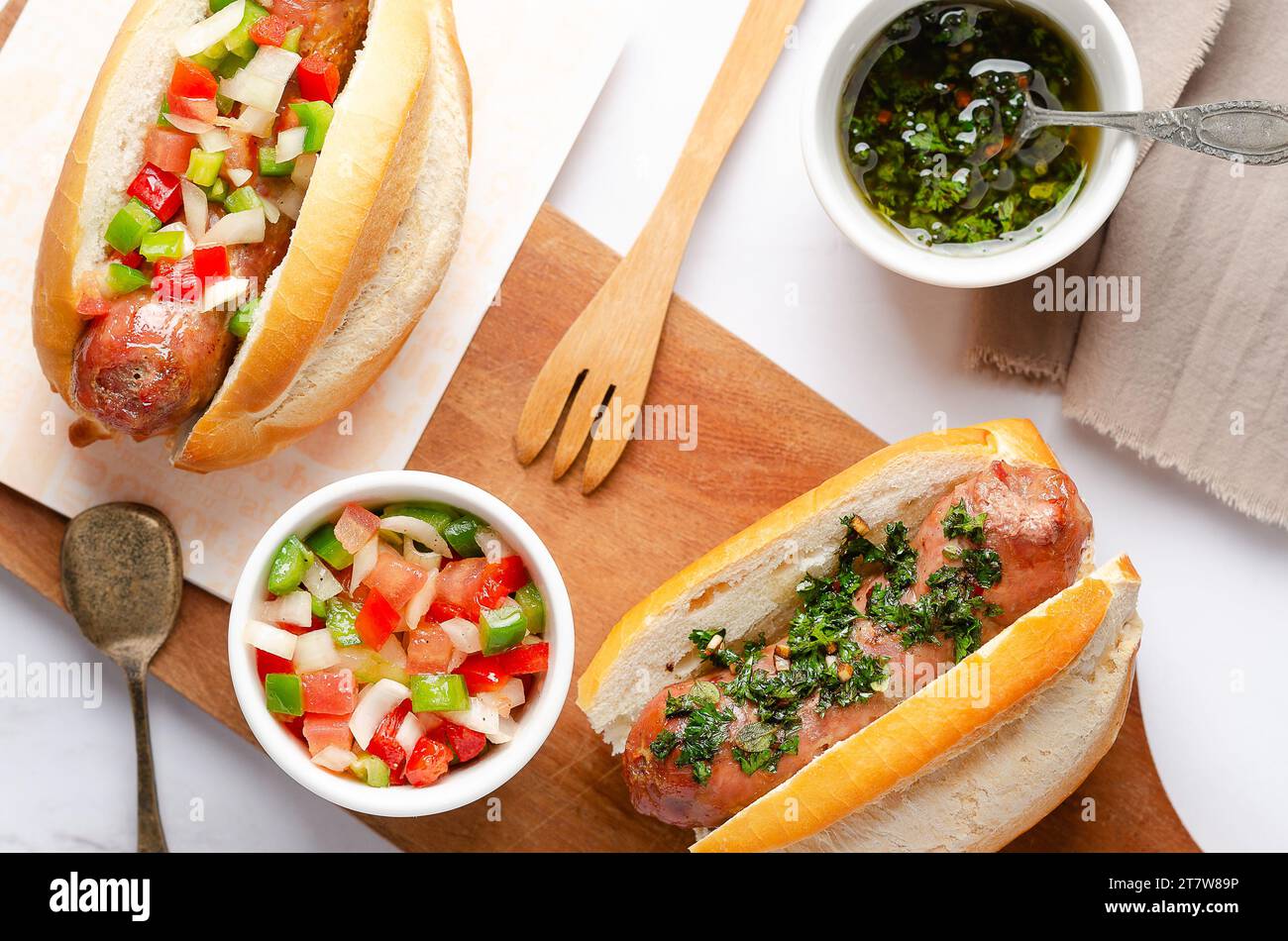 Choripanes with chimichurri and argentinian criolla sauce on a wooden ...