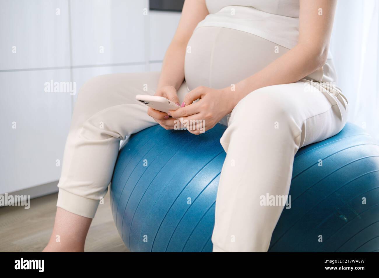 Pregnant woman moves slowly gently rocking body while sitting on rubber ...
