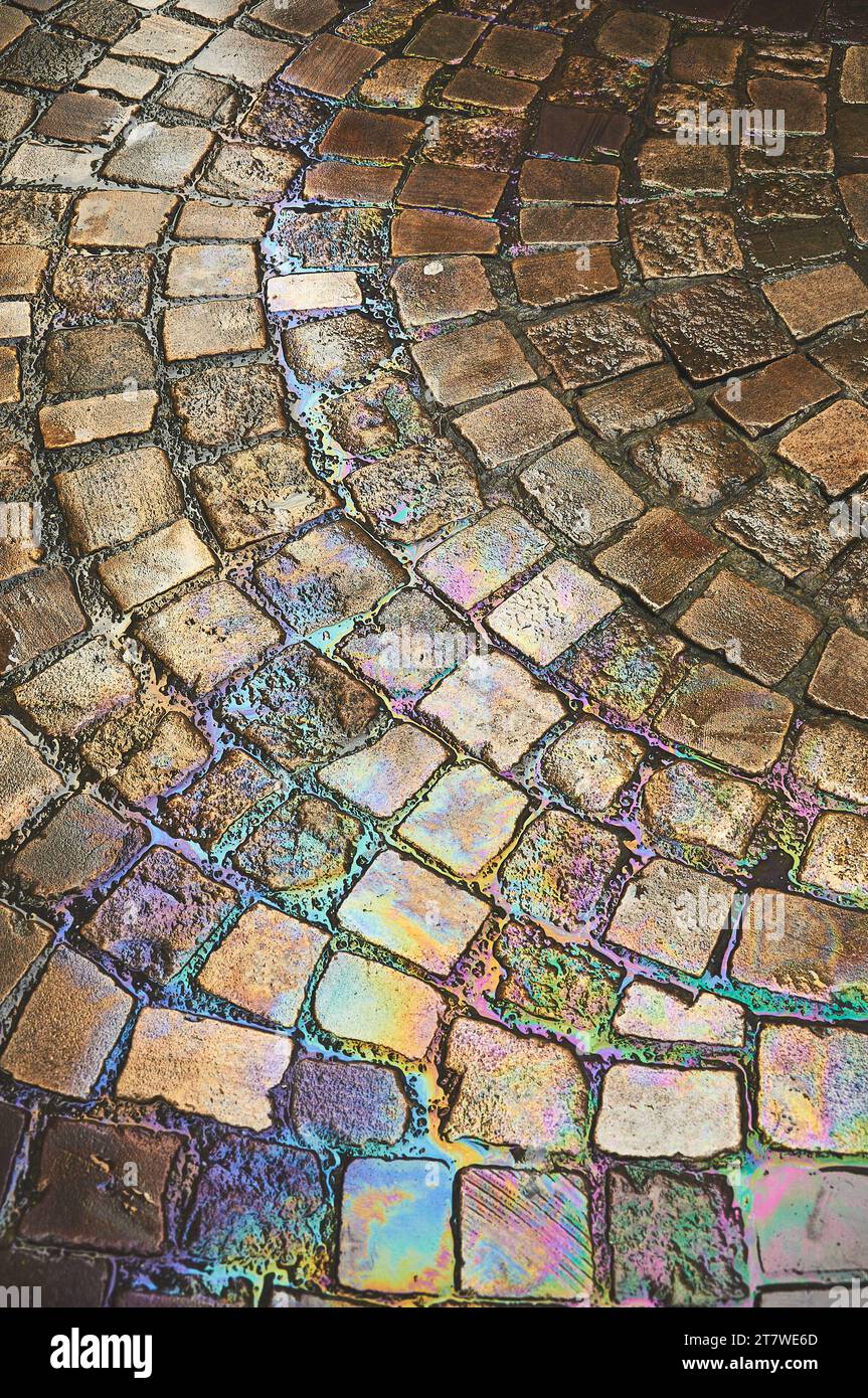Wet cobblestone pavement displaying a colorful rainbow spectrum, post ...