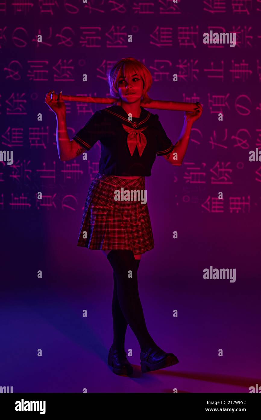 trendy cosplay woman in school uniform with baseball bat on neon purple ...