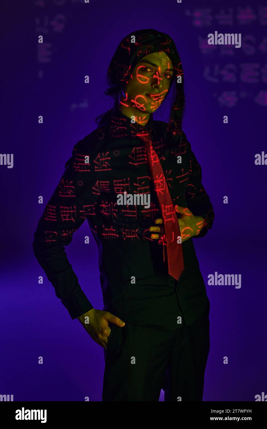 student in black wig and uniform looking at camera in neon light with ...