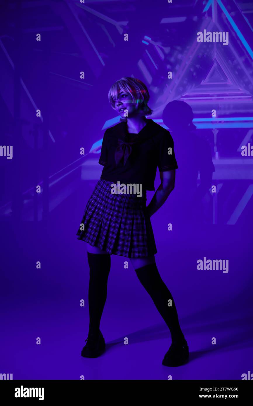 full length of woman in school uniform in blue neon light on abstract ...