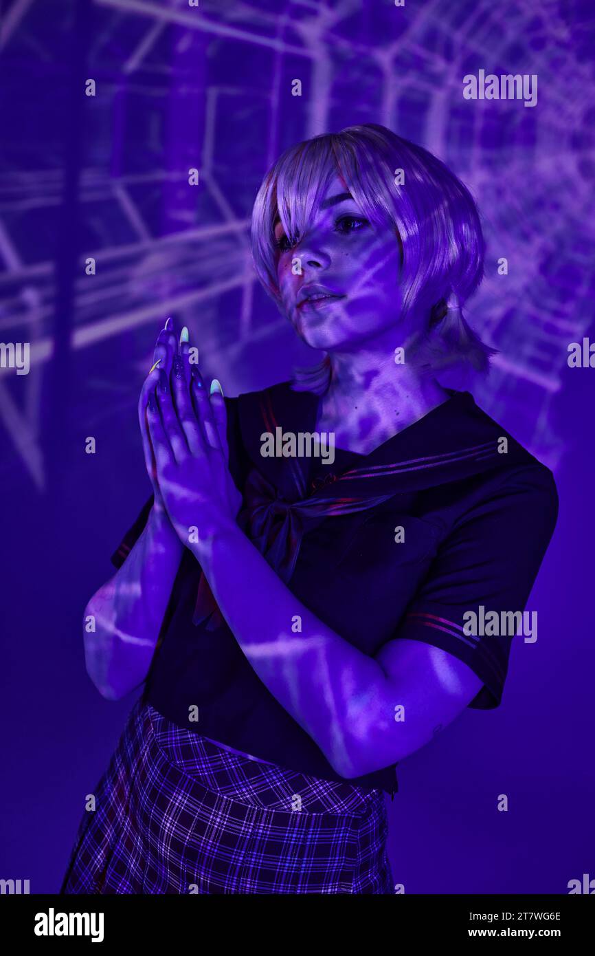 blonde cosplay woman in school uniform standing with praying hands in ...