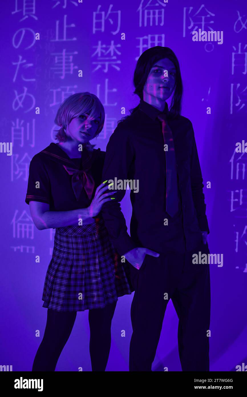 young cosplayers in students uniform and wigs posing in blue neon light ...